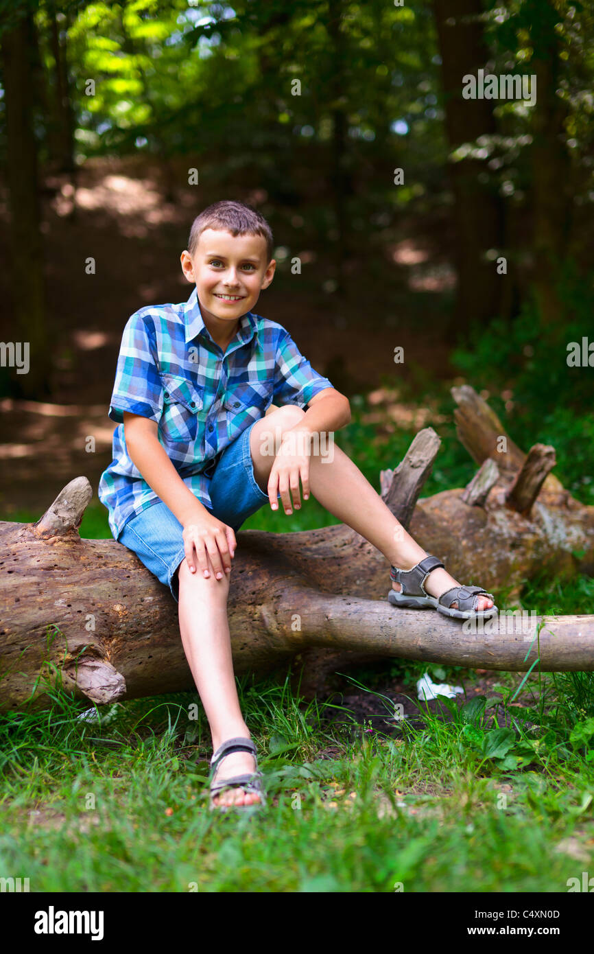 Boy sitting on log in forest hi-res stock photography and images - Alamy