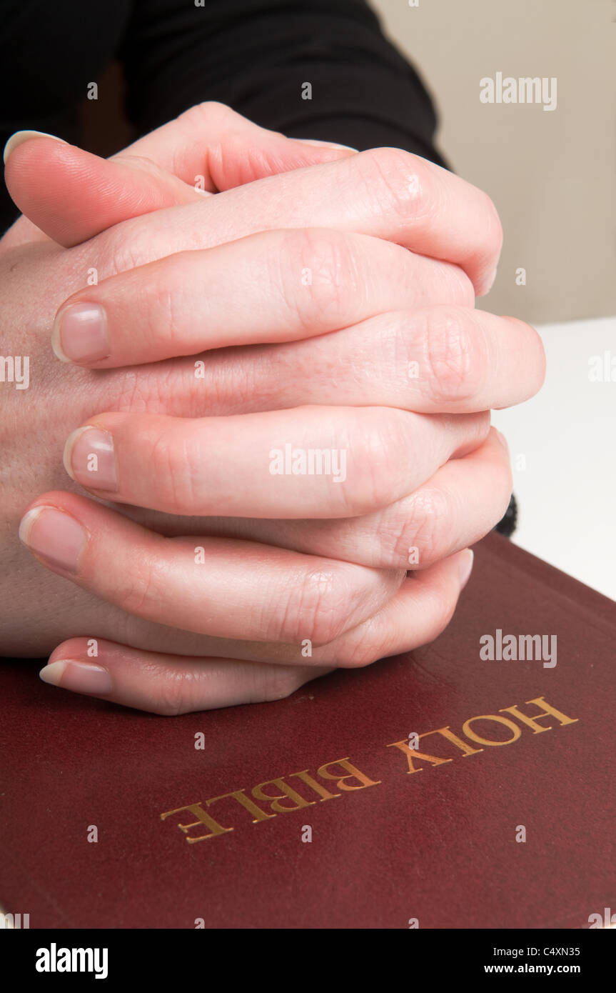 Two praying hands on a Bible Stock Photo - Alamy