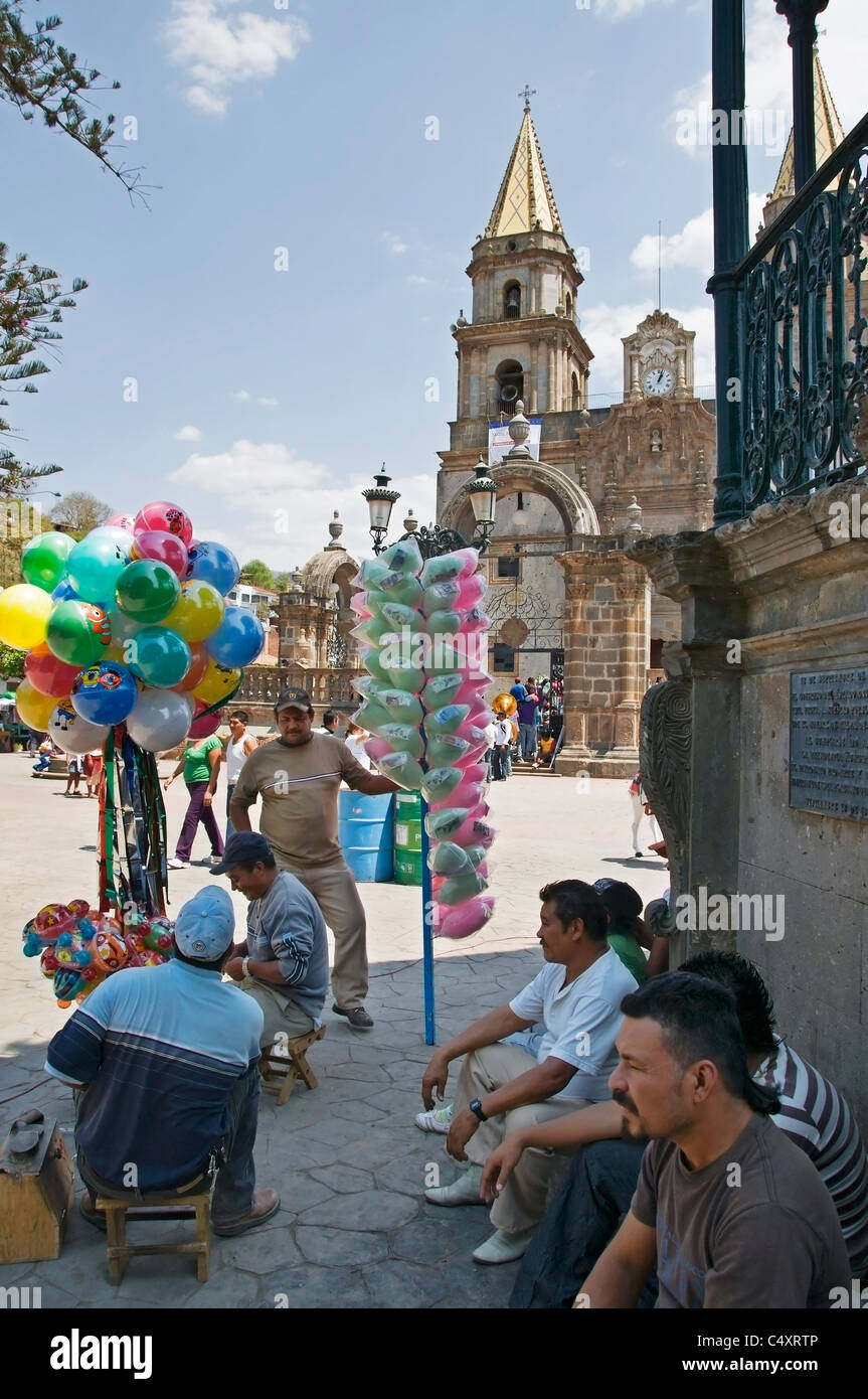 A group of vendors and friends gather in the shade to rest in the plaza ...