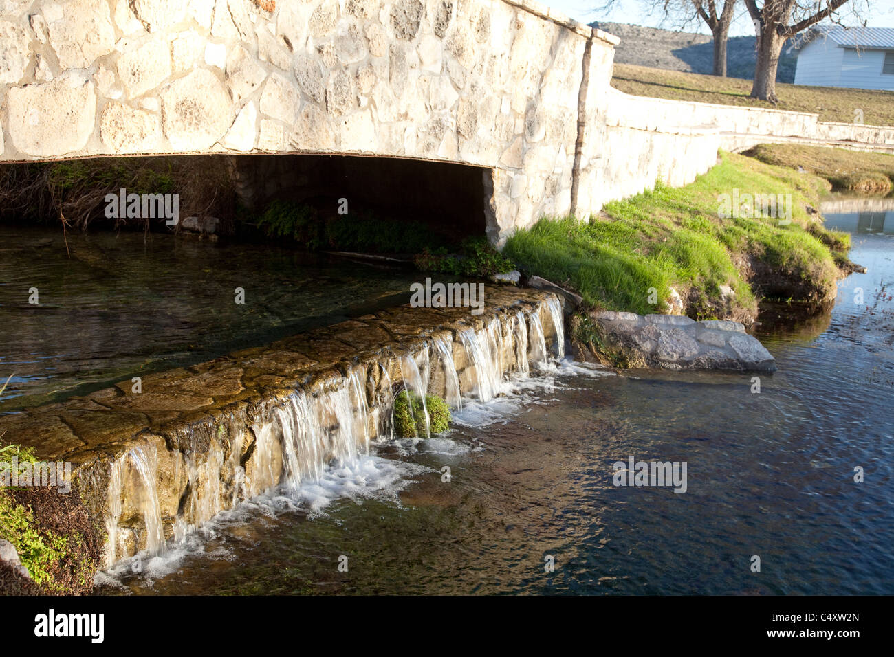 Clear spring water flows over low waterfall into small spring-fed lake ...