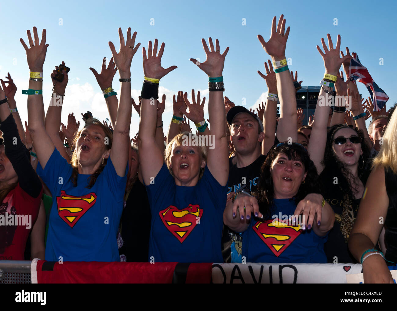 3 women in "superman" tee-shirts raise their hands with the rest of the ...