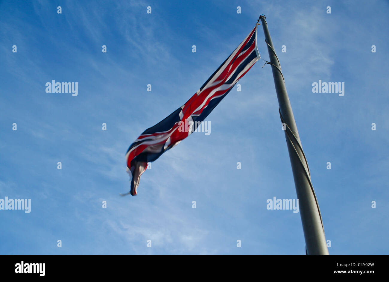 Union Jack Flag flying from flag pole taken against a blue sky with ...