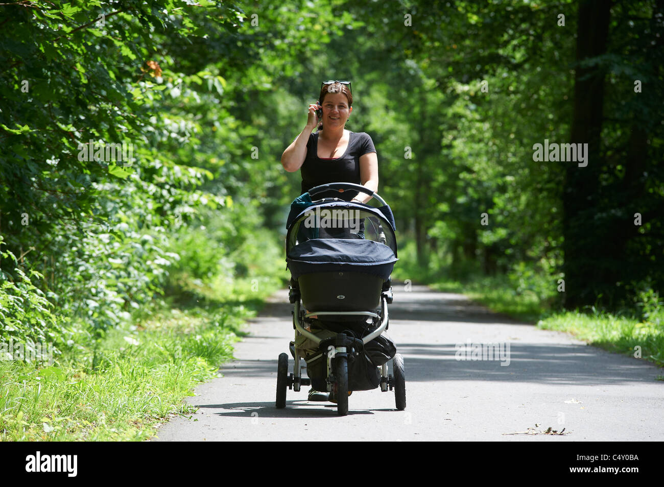 A mother with pushing pram summertime on bike way Stock Photo - Alamy