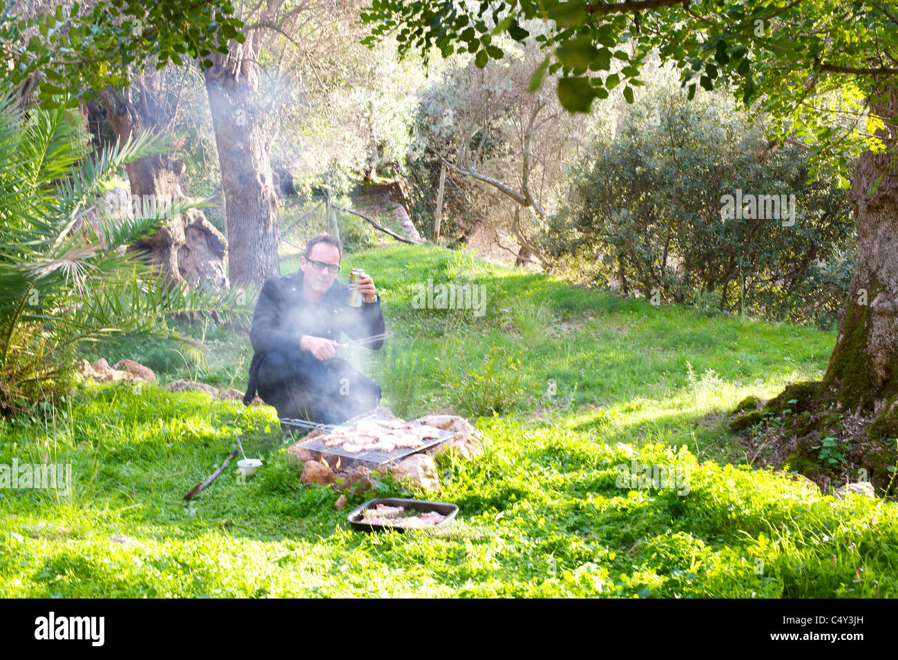 Man cooking a barbeque in olive grove, Majorca, Spain, Iberia, Island ...