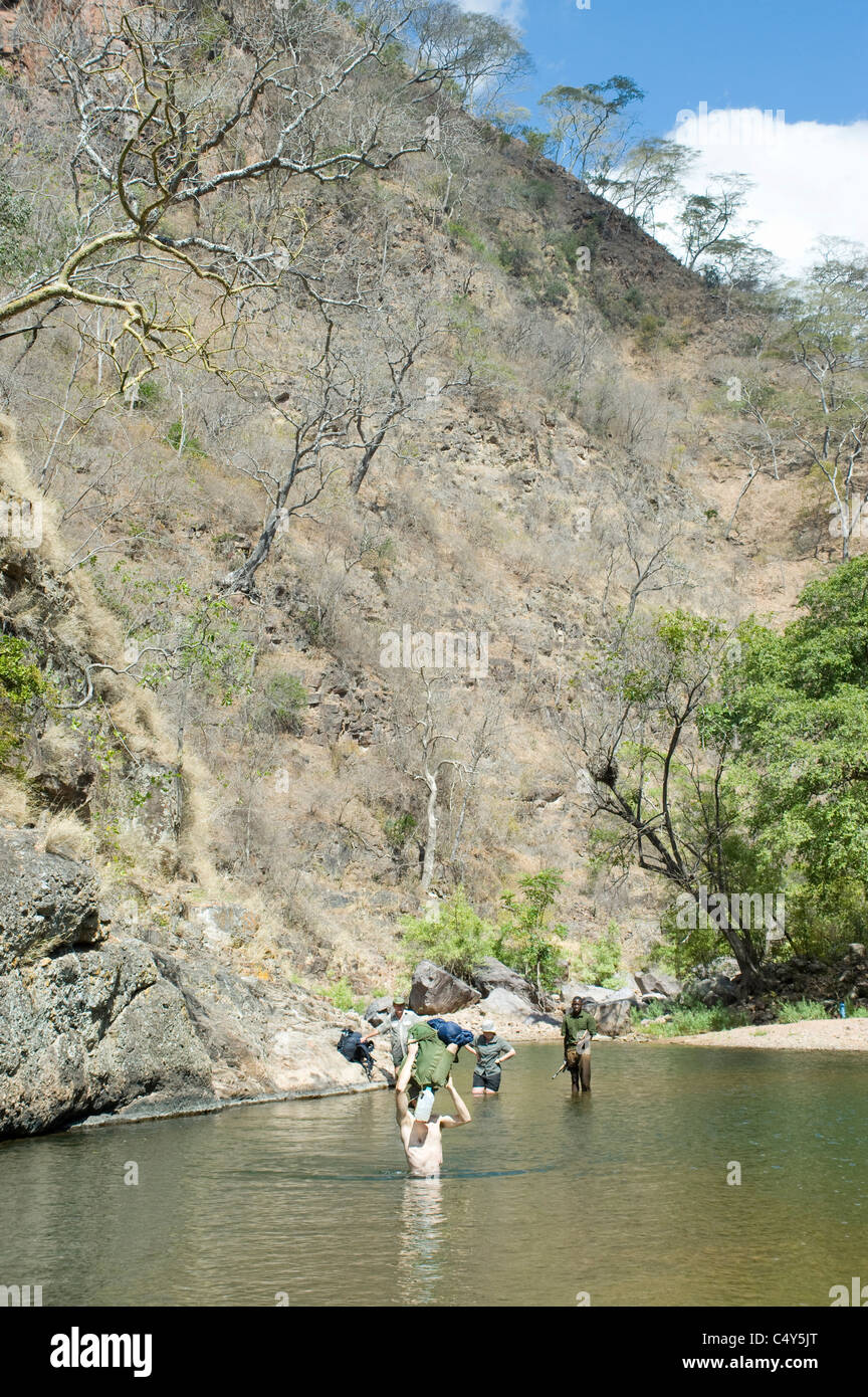 Hikers wade across a deep pool Stock Photo - Alamy