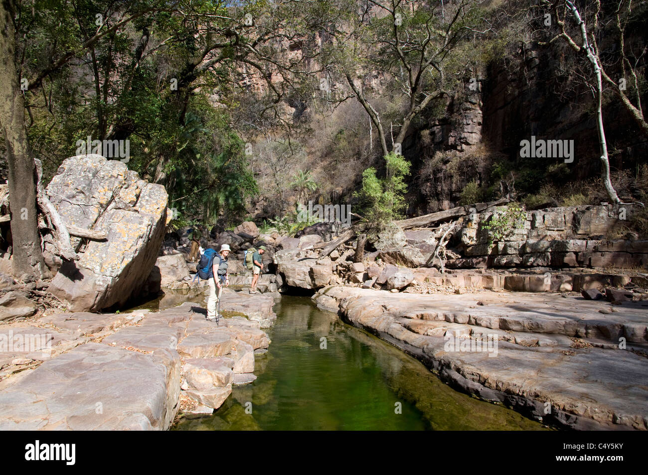 Hikers walk past a deep pool in Chizarira National Park, Zimbabwe Stock ...