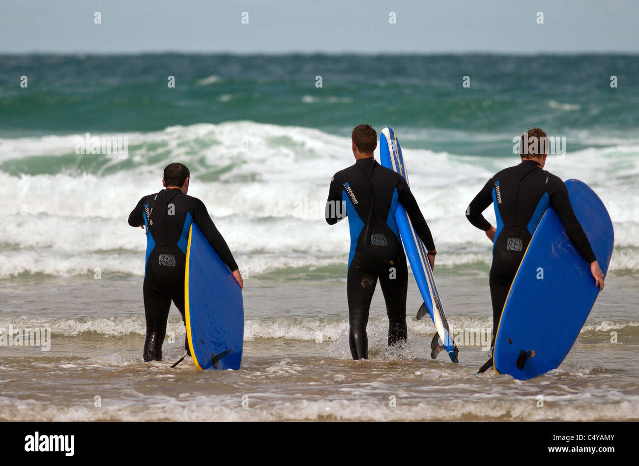 Three surfers walking into the sea Stock Photo - Alamy