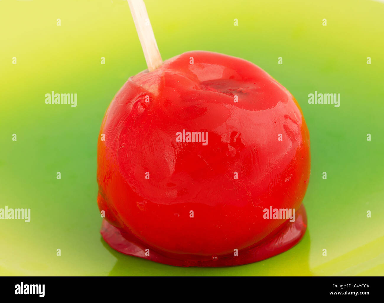 one candied red apple on a green plate background Stock Photo - Alamy