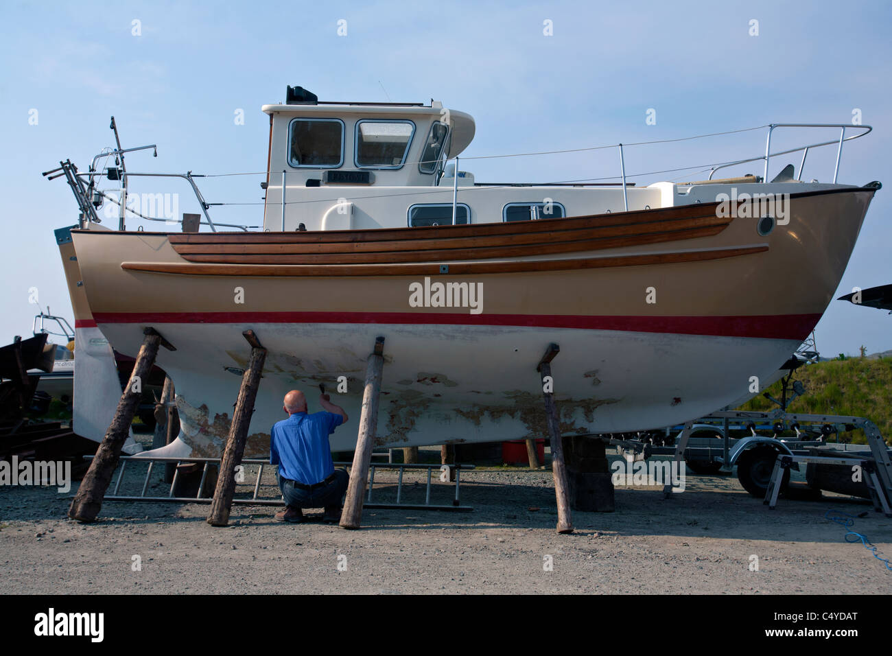 man paints boat in Chandlery crinan boatyard scotland Stock Photo - Alamy