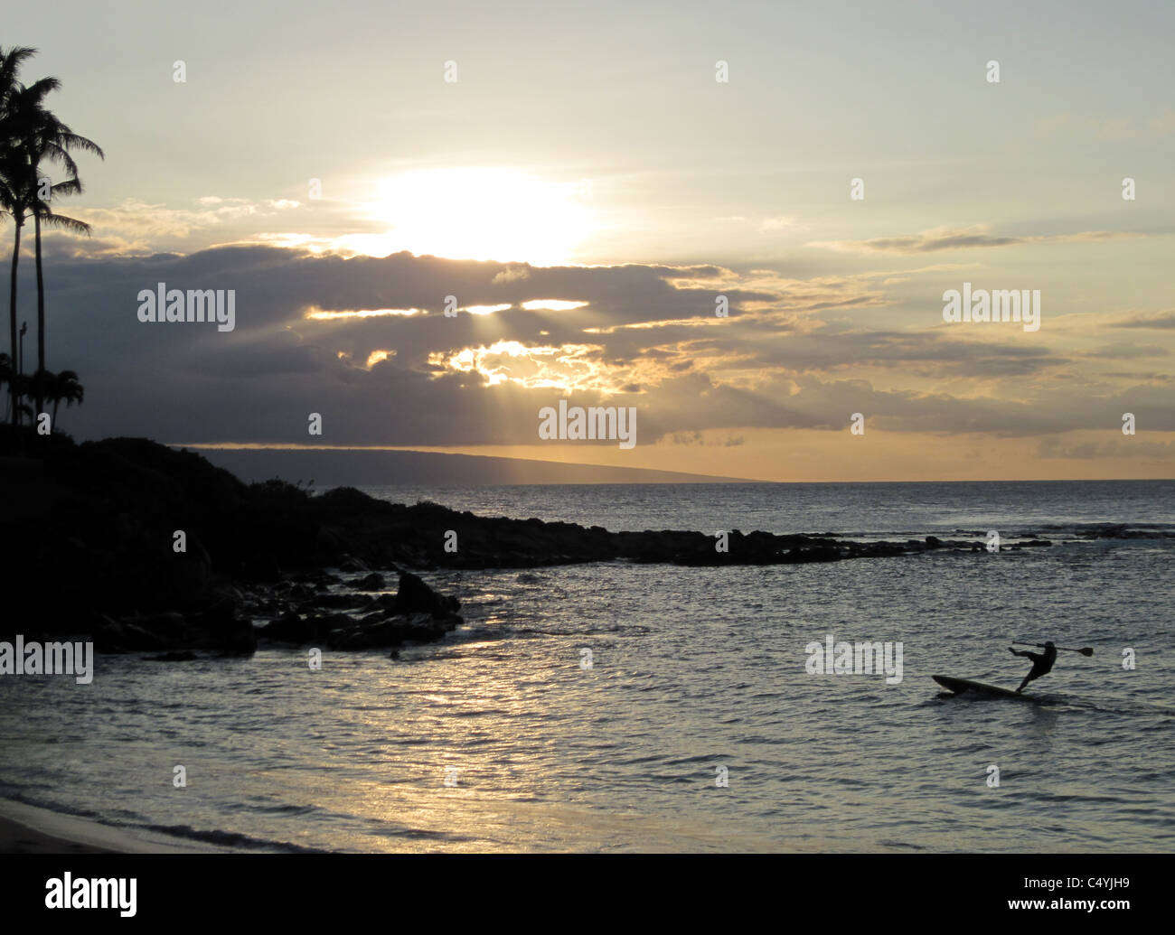 Paddle surfer falling off surfboard at sunset at Kapalua Beach, Maui ...