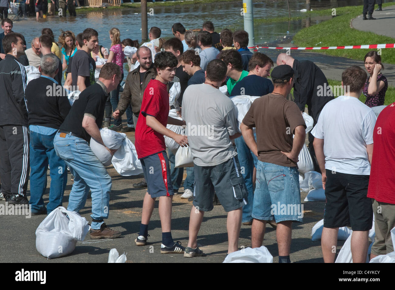 Volunteers standing in human chain carrying sandbags during 2010 flood ...