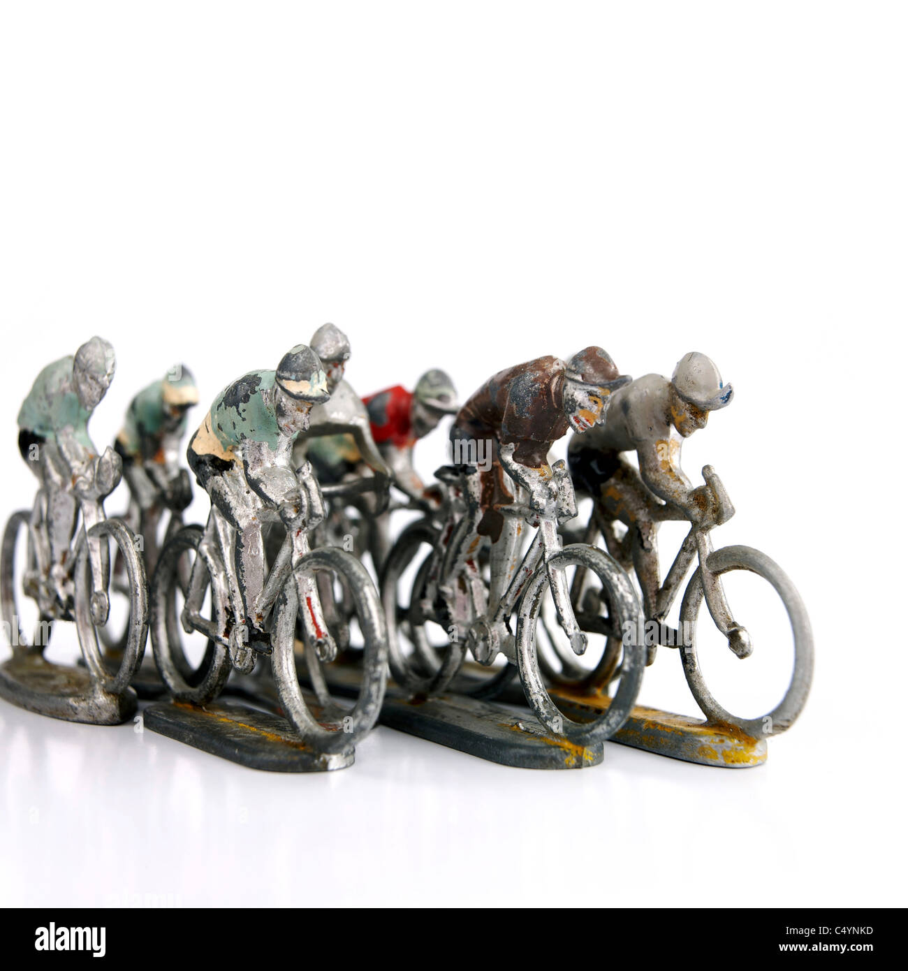 Vintage toy cyclists racing on bikes captured against a white ...