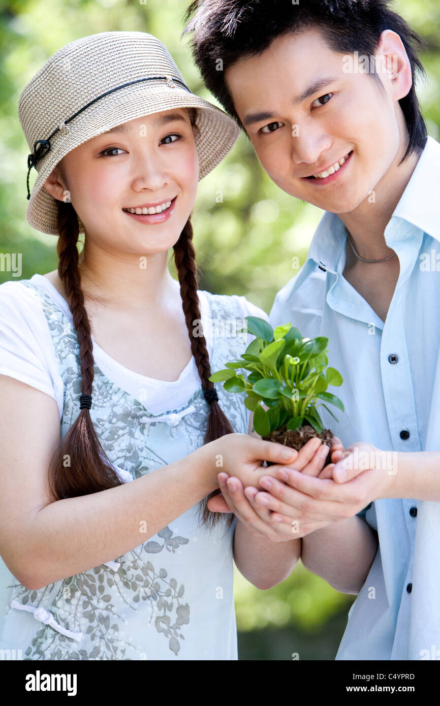 Young Couple Holding Plant Together Stock Photo - Alamy