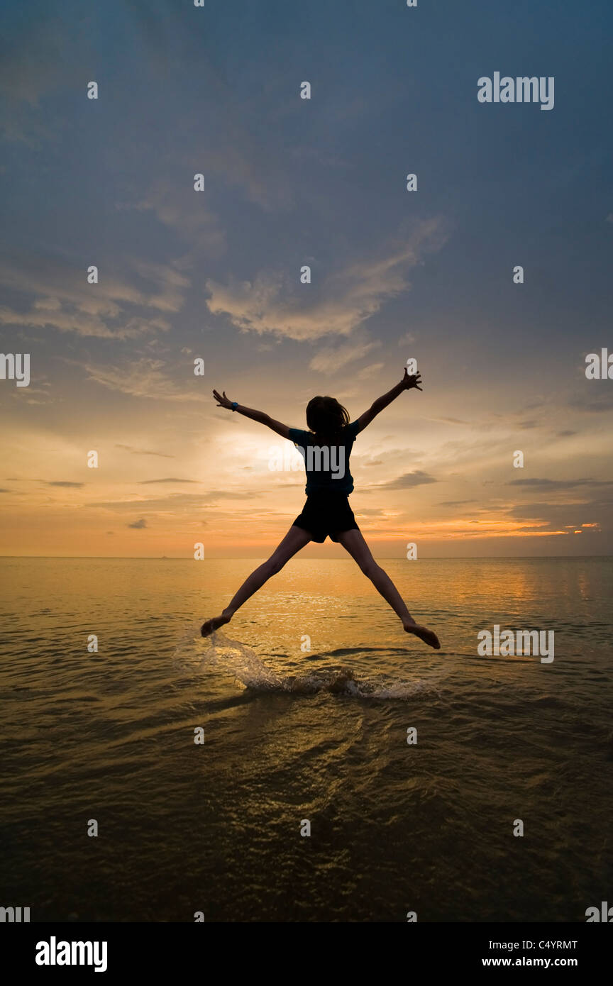 A young woman doing a star jump, jumping for joy and enjoying her ...