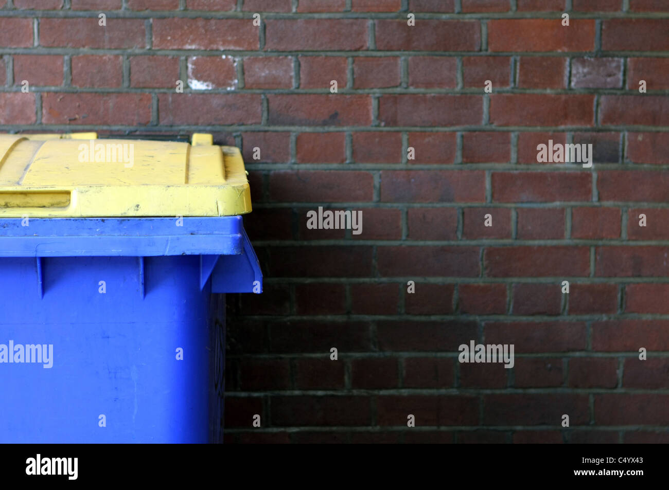Part of a commercial wheelie bin in front of a brick wall Stock Photo ...