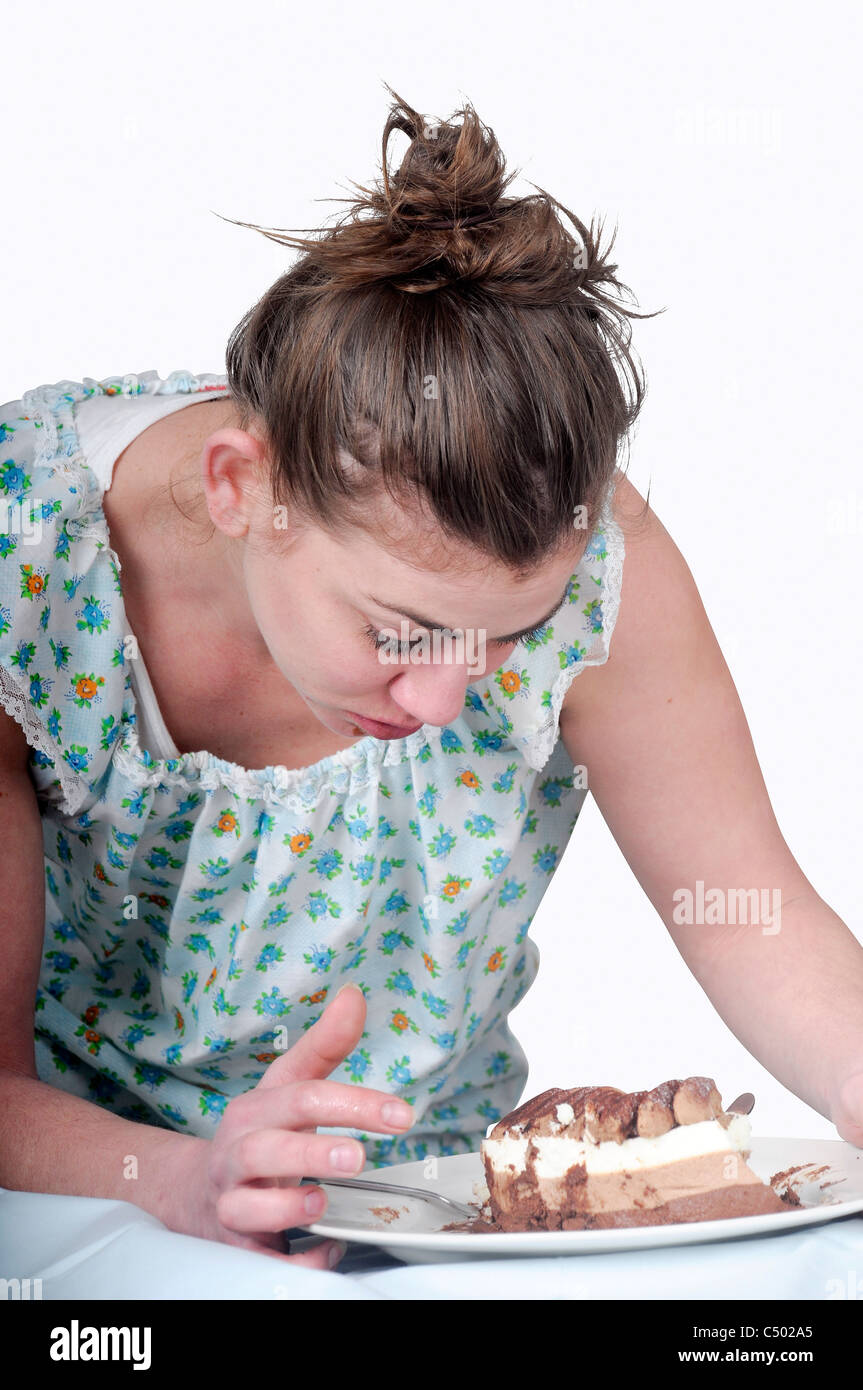 Female eating disorder. Young woman craves a cream cake late at night ...