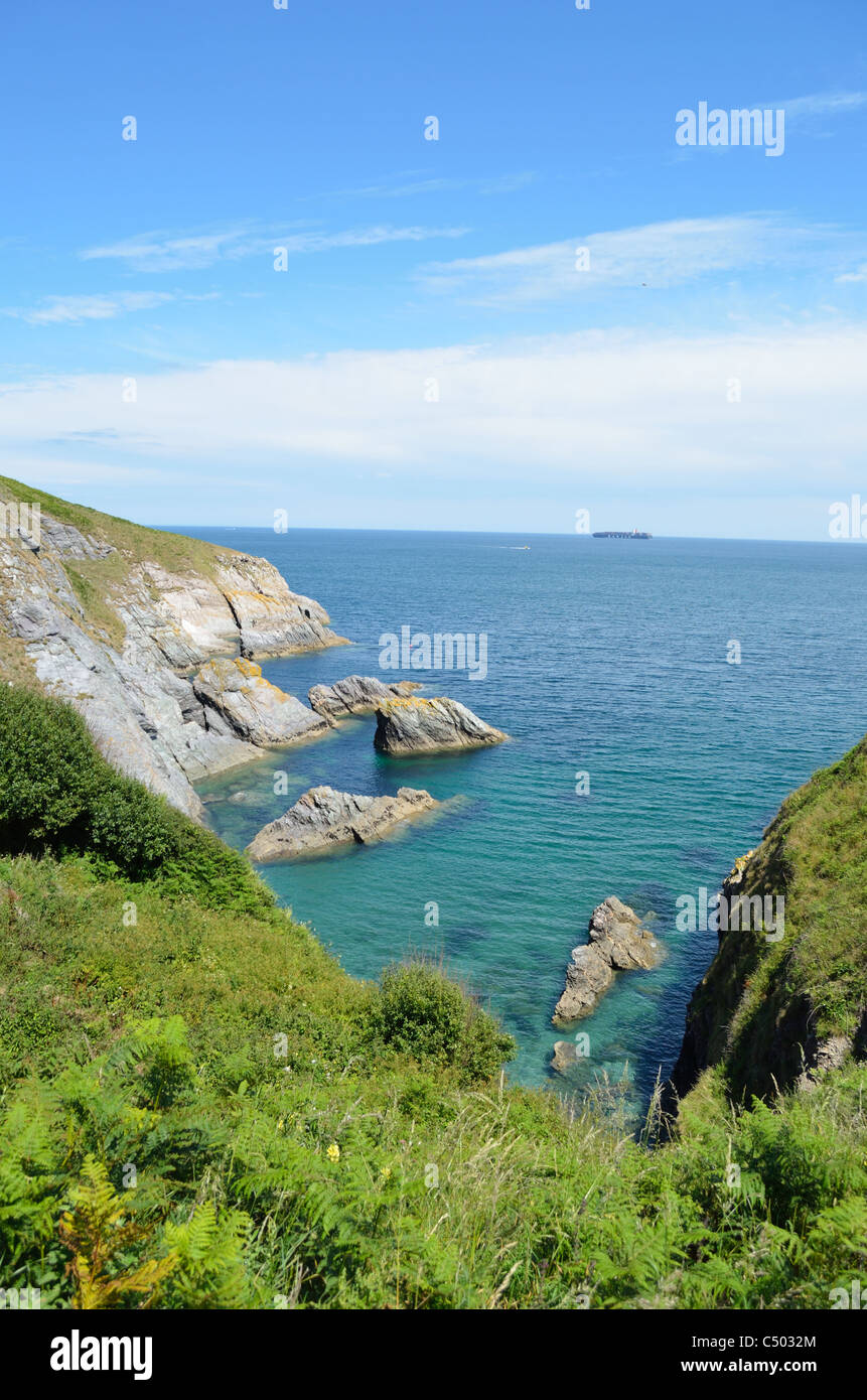 A small Cove with a cargo ship on the horizon Stock Photo - Alamy