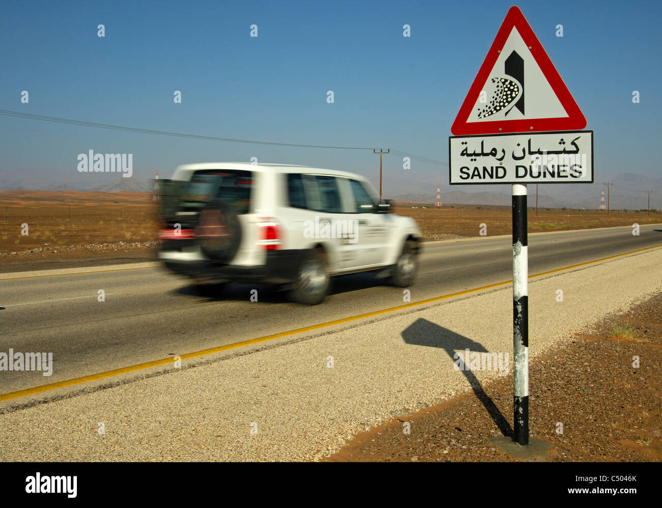Road sign warning in English and Arabic of shifting sand dunes at a ...