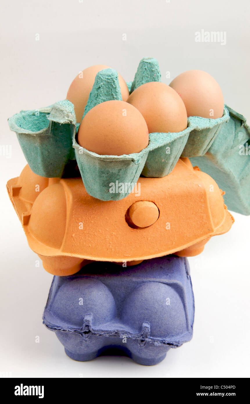 Stack of colorful egg cartons with brown eggs balanced on top in a ...