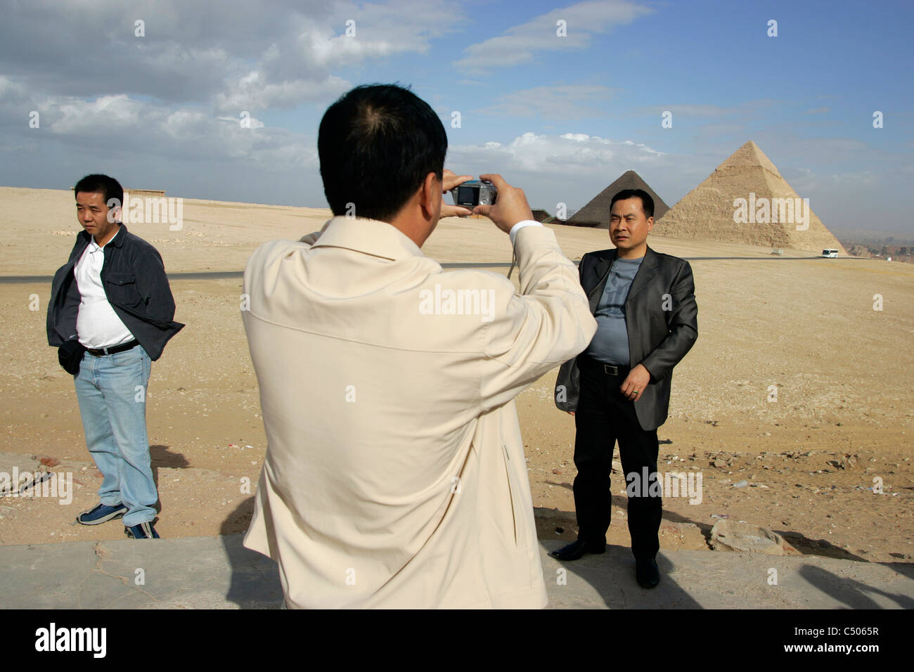 Tourists pose for and take photographs with the Great Pyramids of Giza ...
