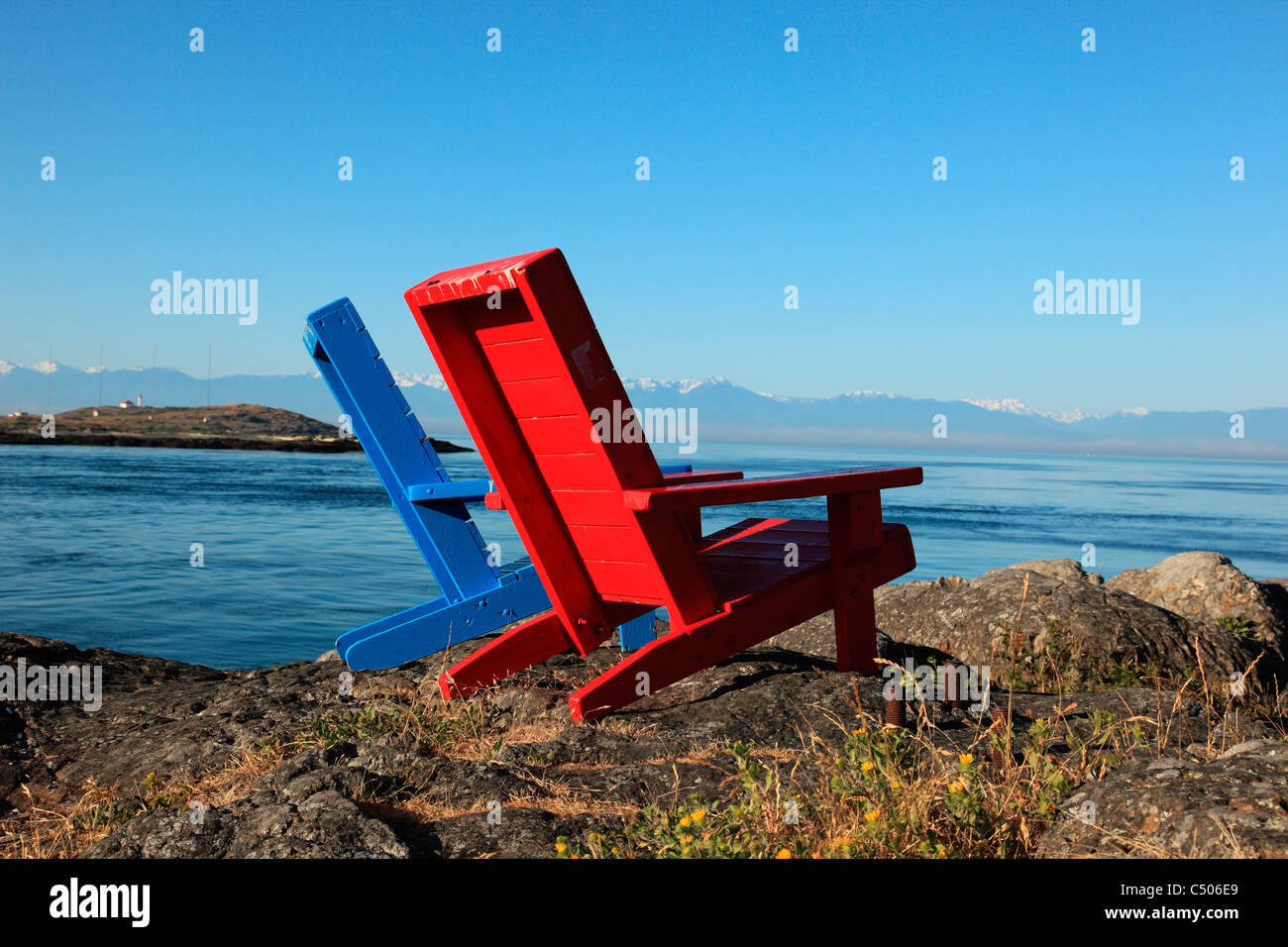 Red and Blue chairs sitting on rocks looking out to the pacific ocean ...
