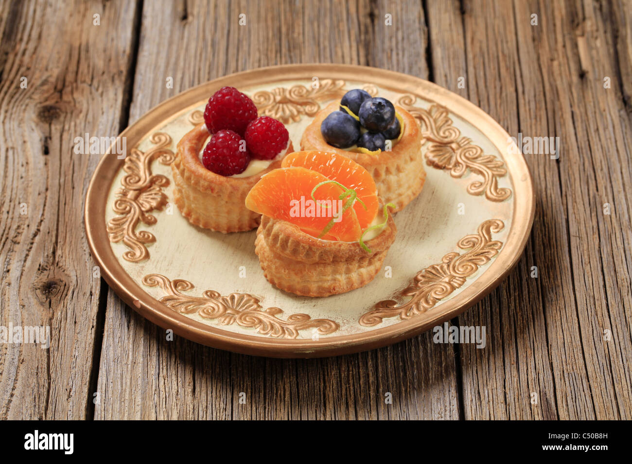 Custard filled puff pastry shells topped with fresh fruit Stock Photo ...