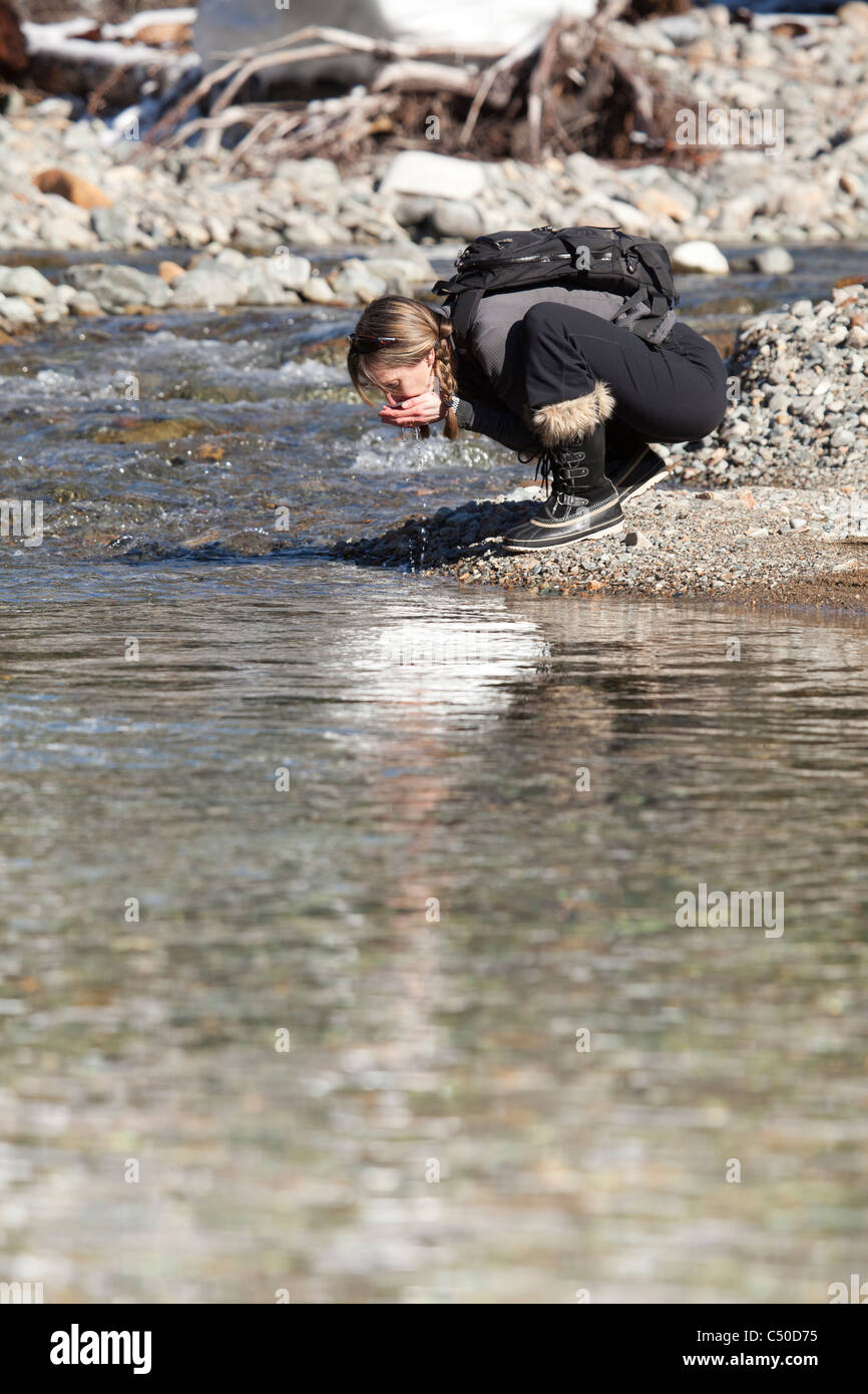 Caucasian hiker drinking from remote stream Stock Photo - Alamy