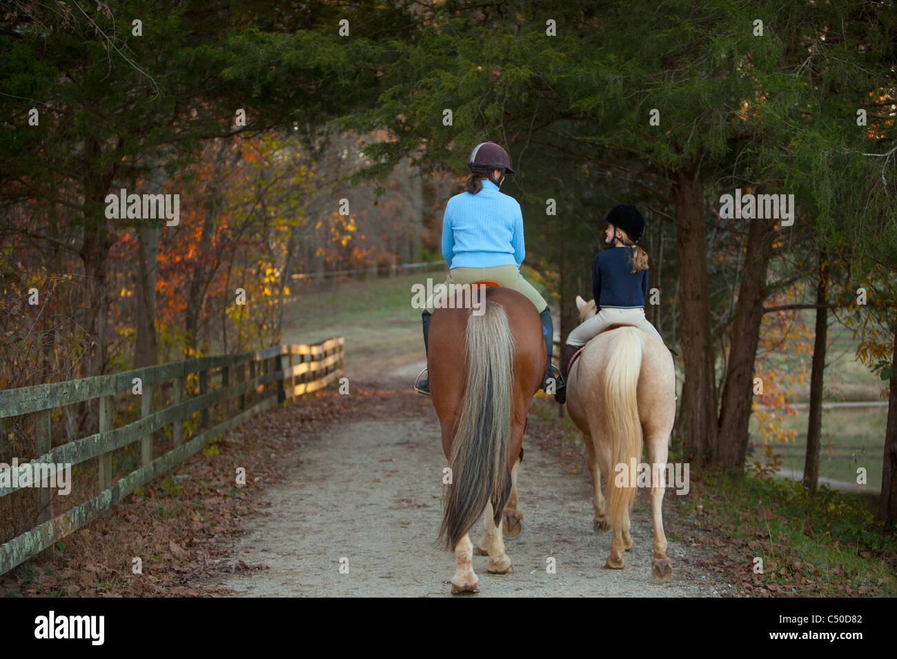 Caucasian girl and trainer riding horses Stock Photo - Alamy