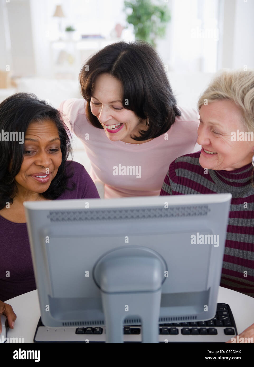 Friends using computer together Stock Photo - Alamy