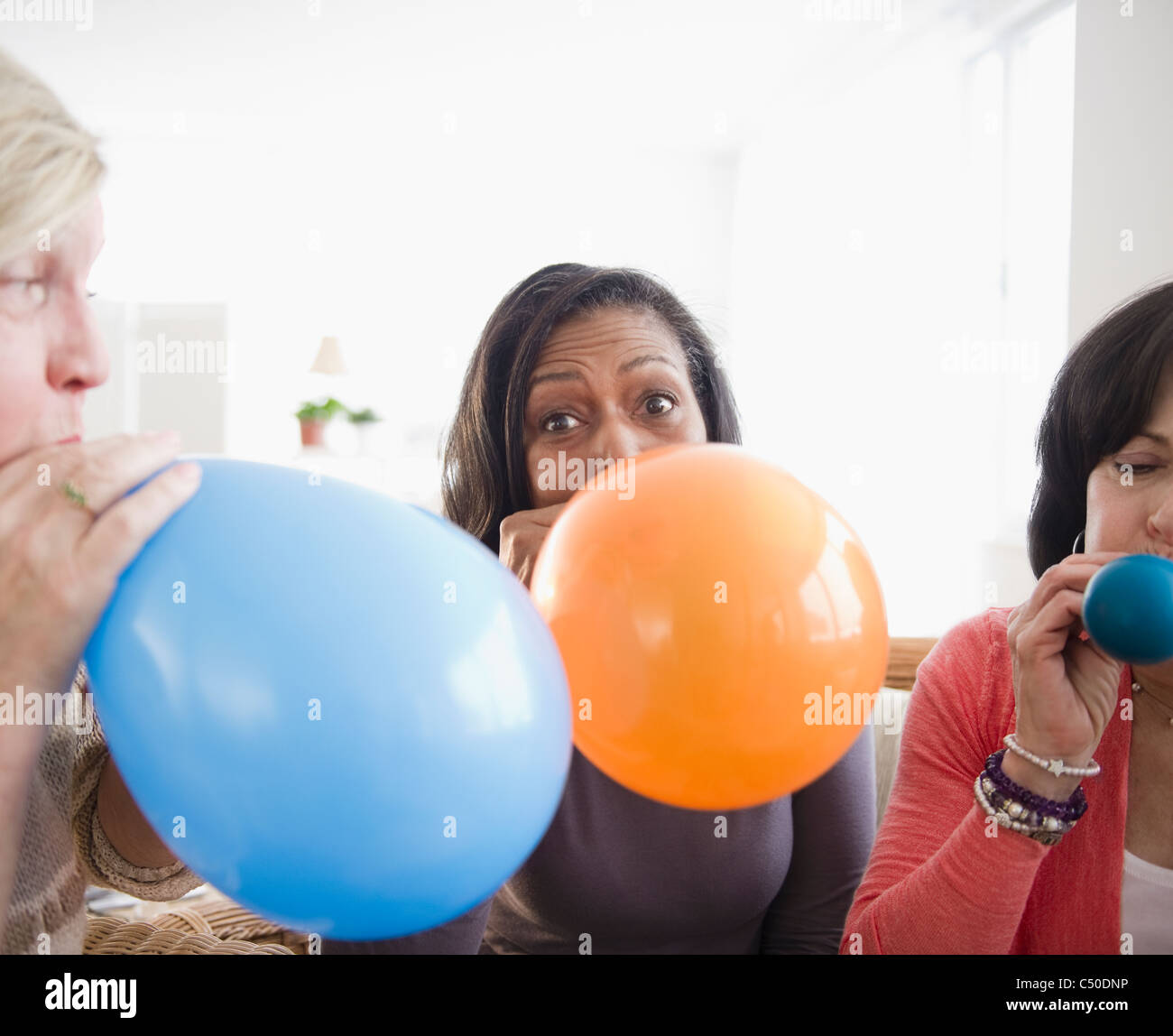 Friends blowing up balloons together Stock Photo - Alamy