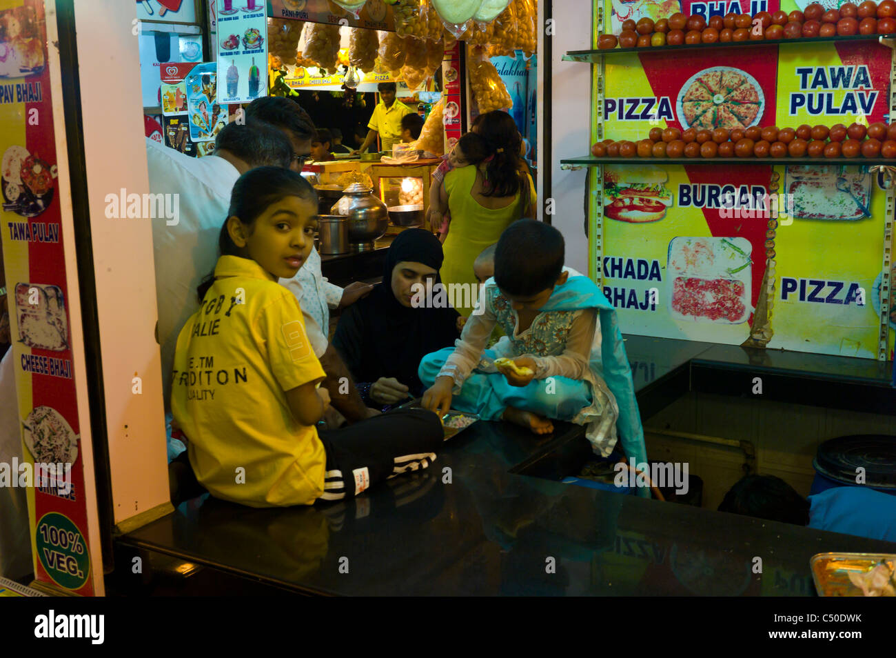 A muslim family at a food stall in a night market at Juhu Beach, Mumbai ...