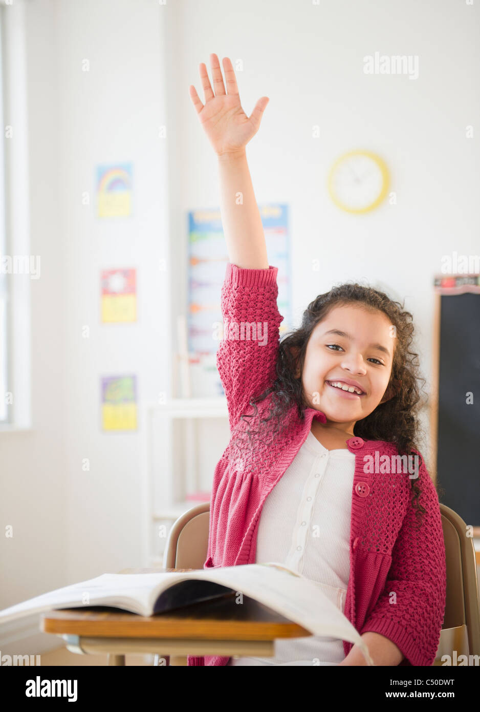 Hispanic girl raising hand in classroom Stock Photo - Alamy