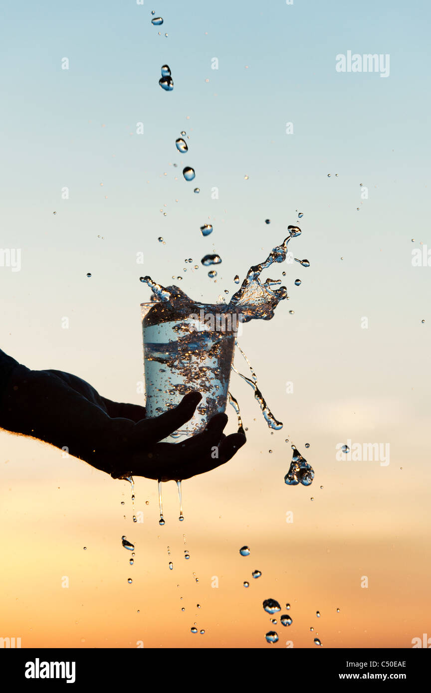 Water being poured into a plastic cup at sunset. Silhouette. India ...