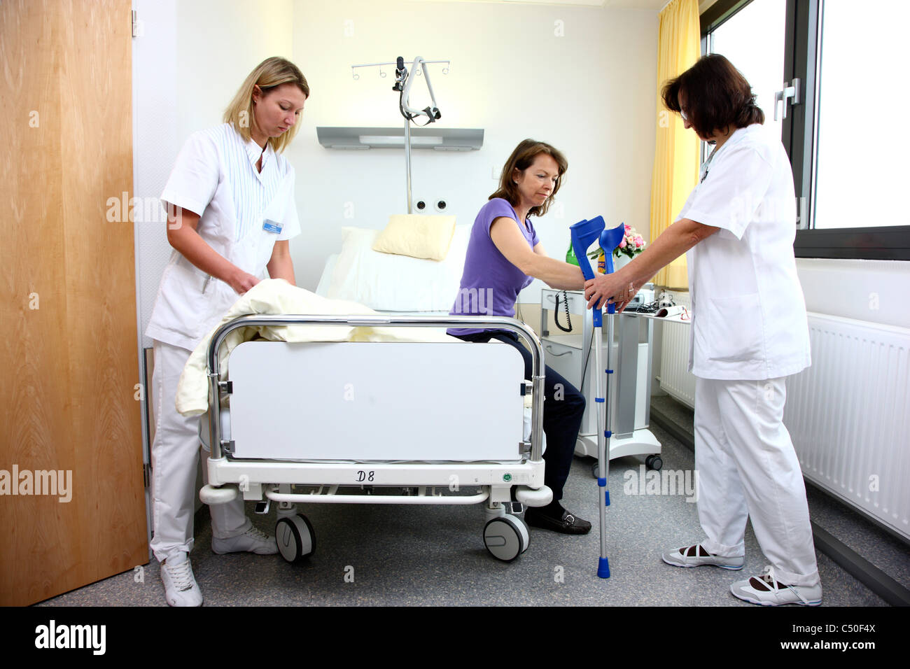 Hospital.Patient is making first steps after surgery, helped by a nurse ...