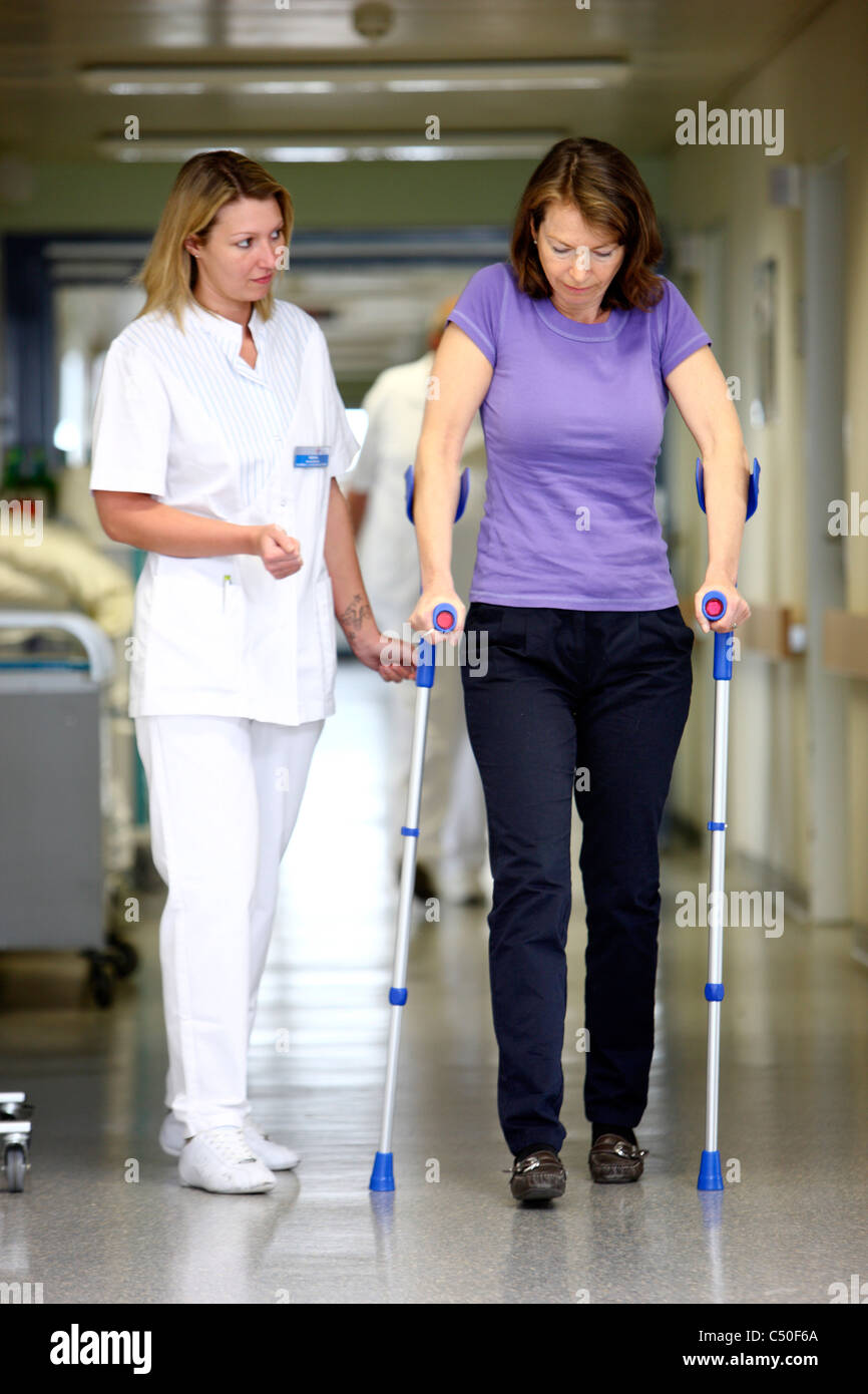 Hospital.Patient is making first steps after surgery, helped by a nurse ...