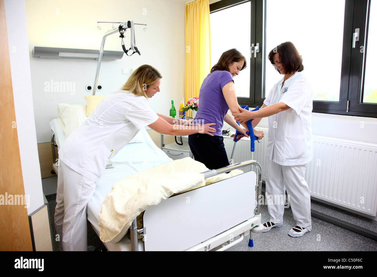 Hospital.Patient is making first steps after surgery, helped by a nurse ...