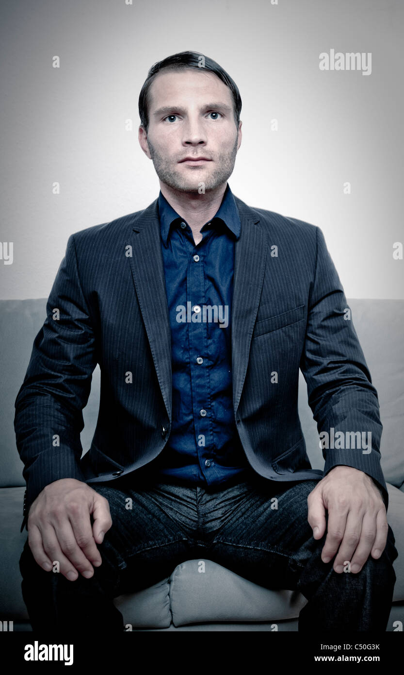 Man wearing a suit sitting on a sofa, men's fashion Stock Photo - Alamy