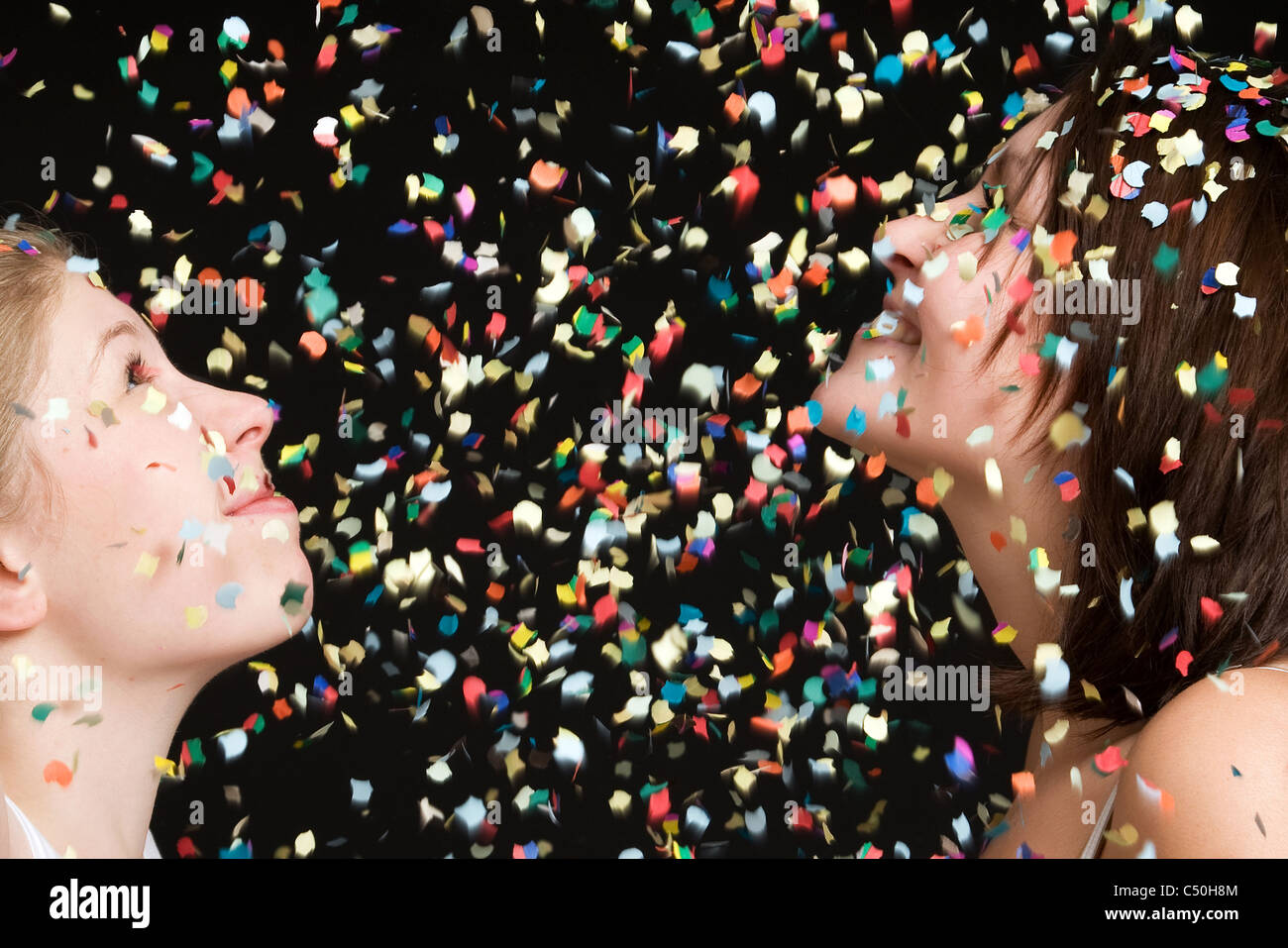 Two young women in a rain of confetti Stock Photo - Alamy