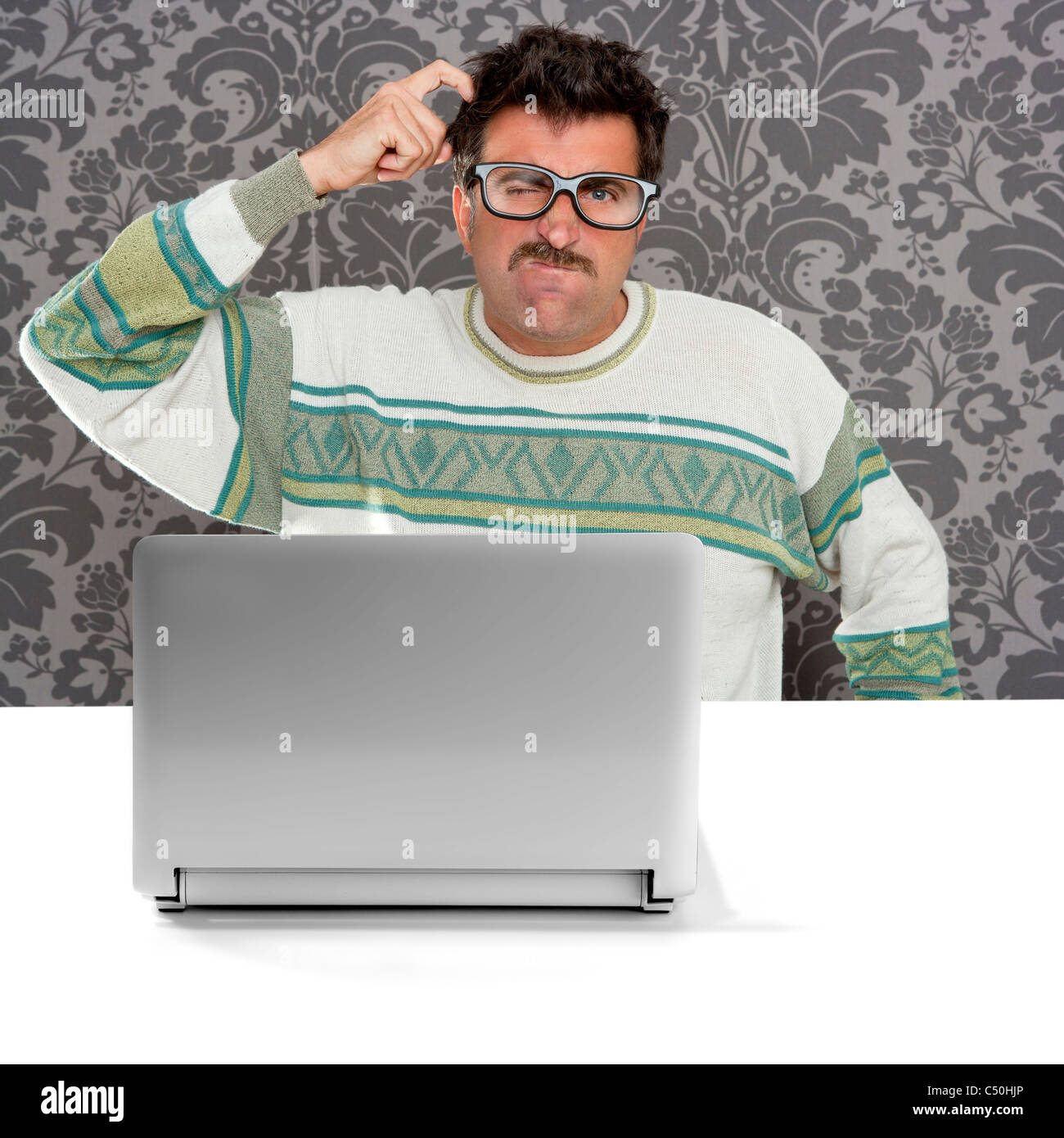 Nerd pensive man with glasses and silly expression in front a laptop ...