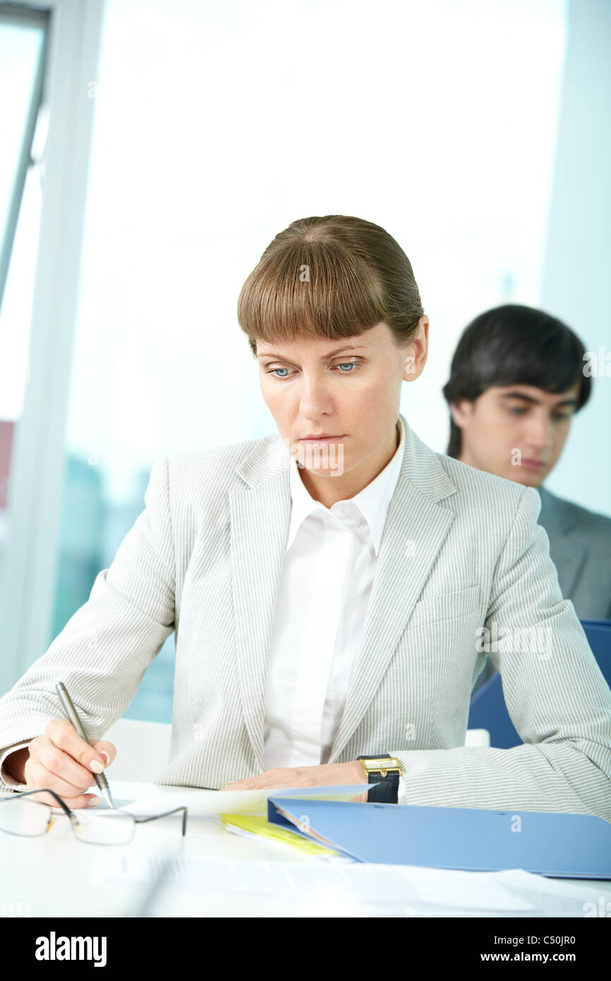 Portrait of serious woman working with papers in office Stock Photo - Alamy