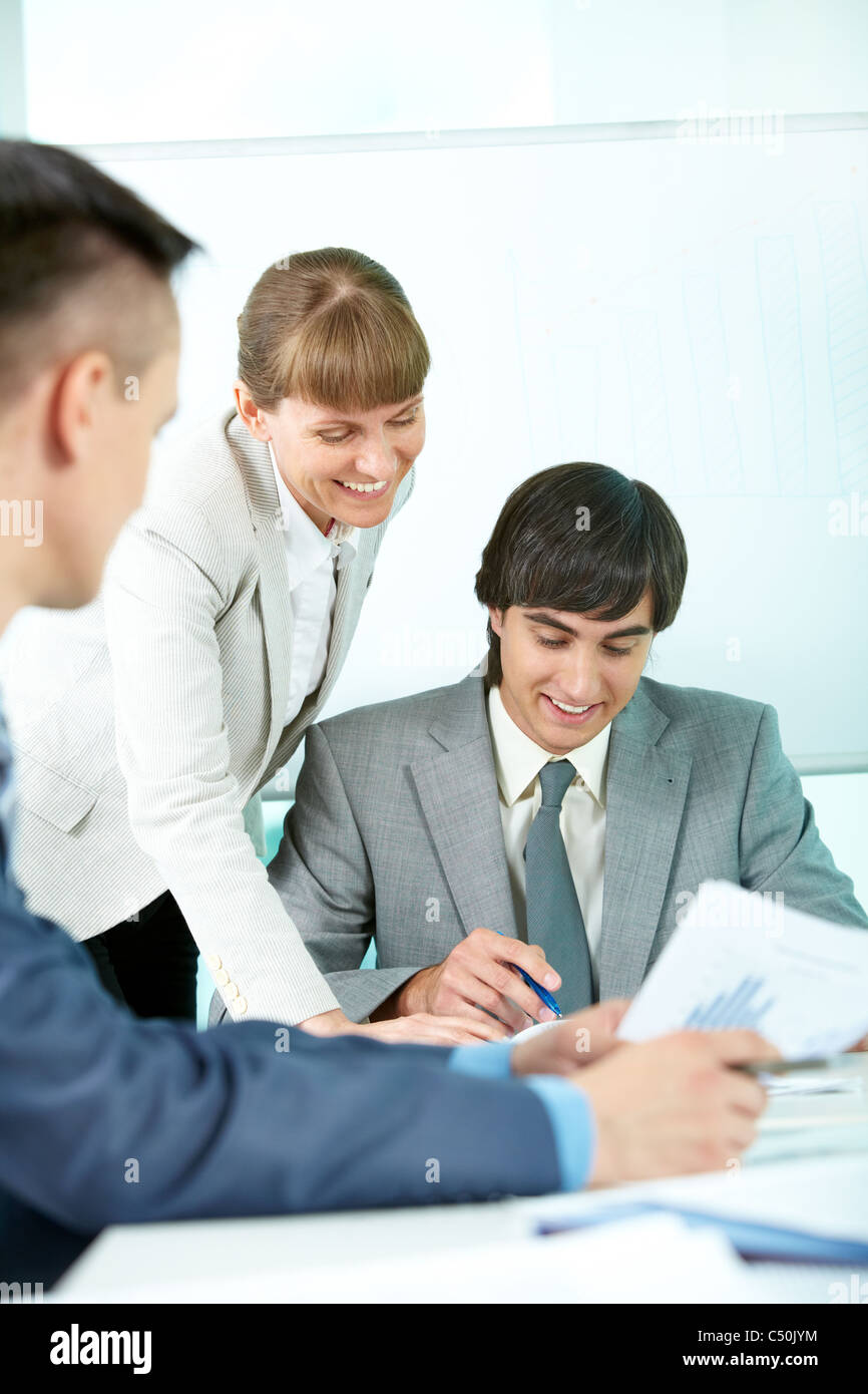 Portrait of smiling partners looking through papers in office Stock ...