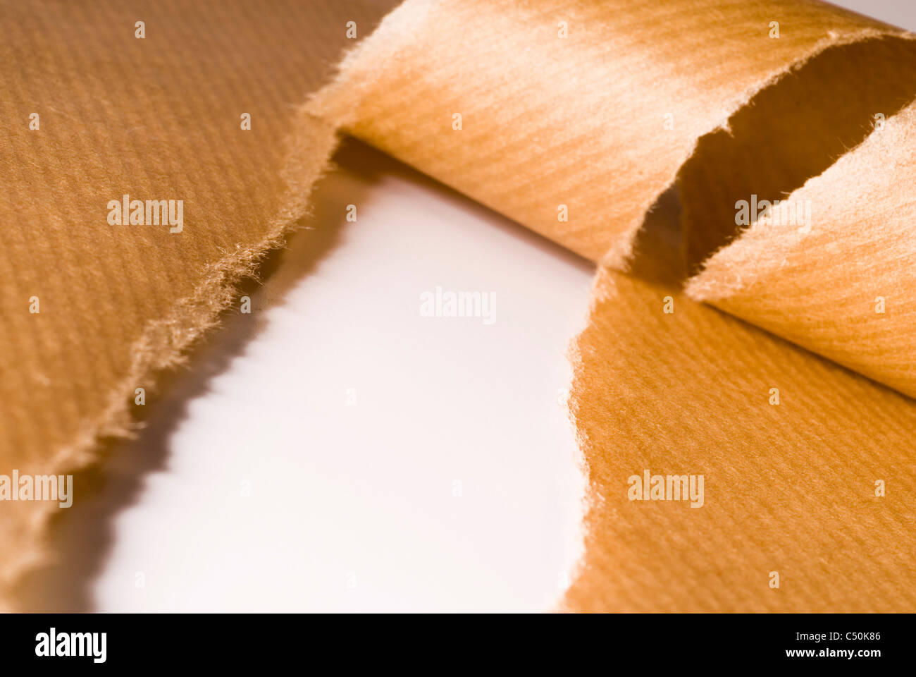 Ripped parcel paper revealing white background Stock Photo - Alamy