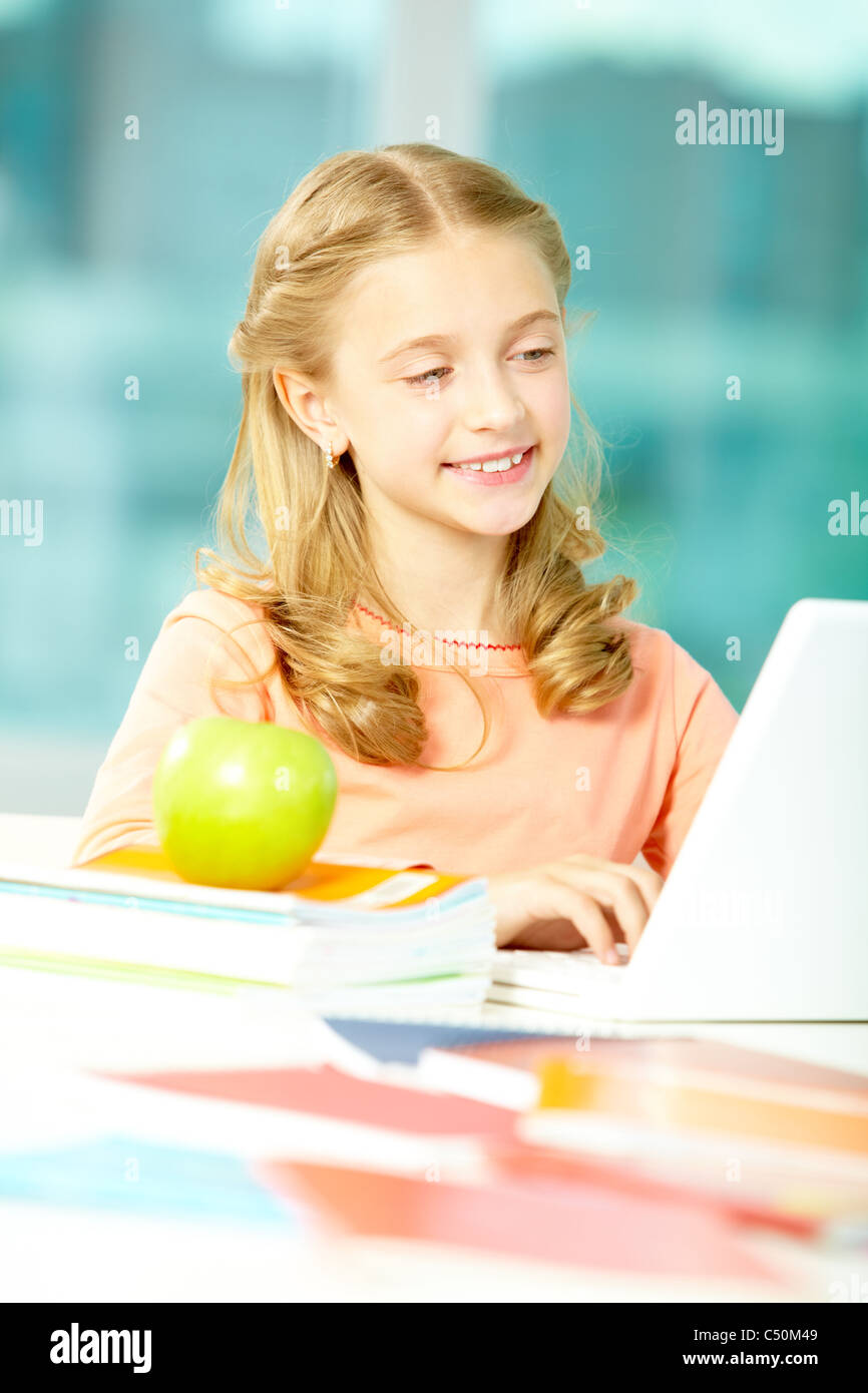 Portrait of smart schoolgirl sitting in classroom and typing Stock ...