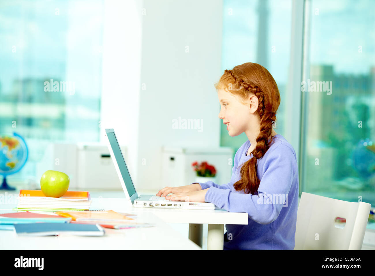 Portrait of smart schoolgirl sitting in classroom and typing Stock ...