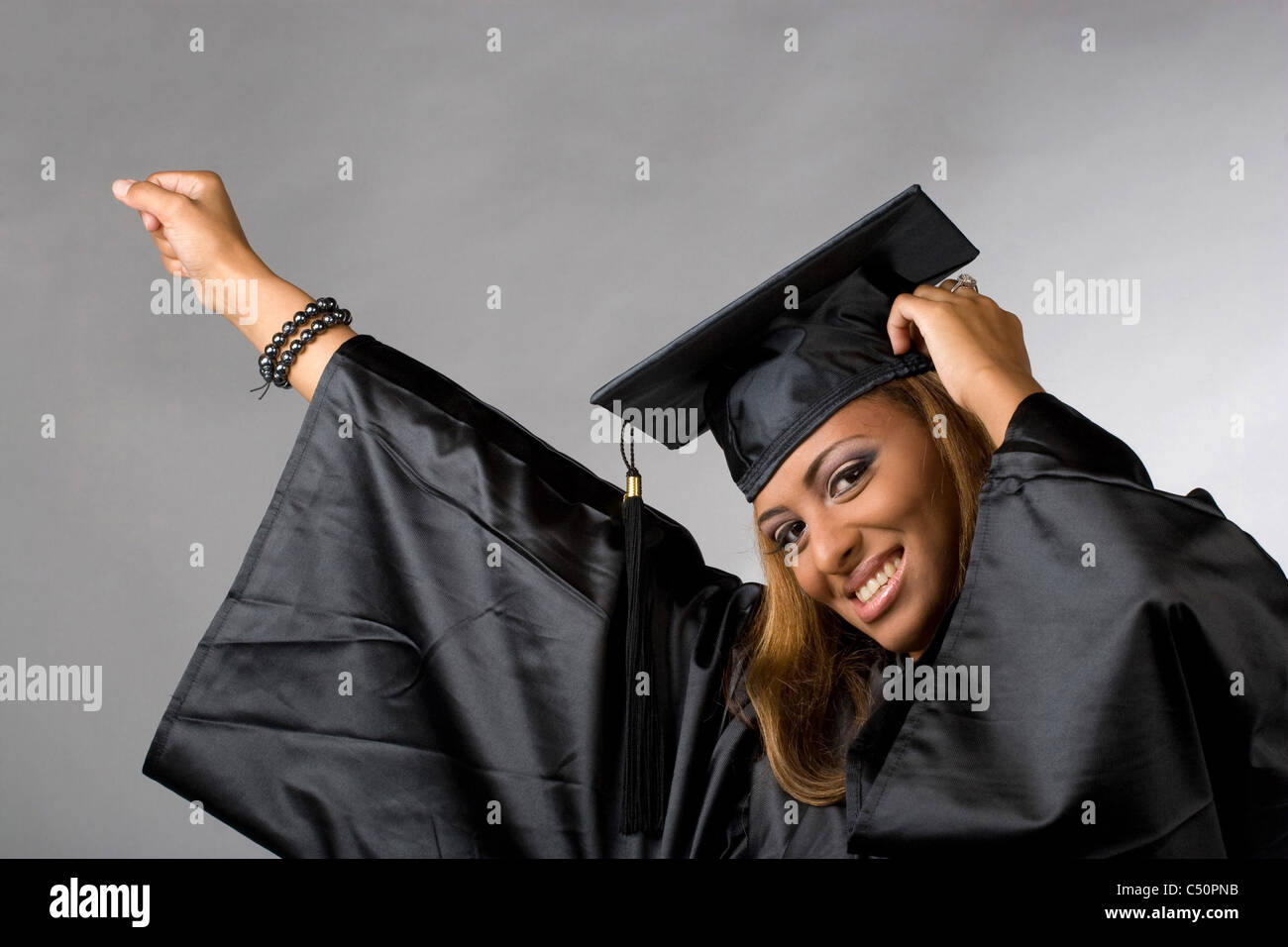A recent graduate posing in her cap and gown isolated over a silver ...