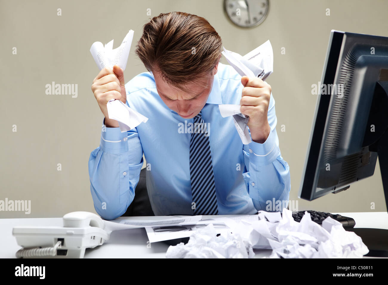 Portrait of stressed businessman with crumbled papers in hands at ...