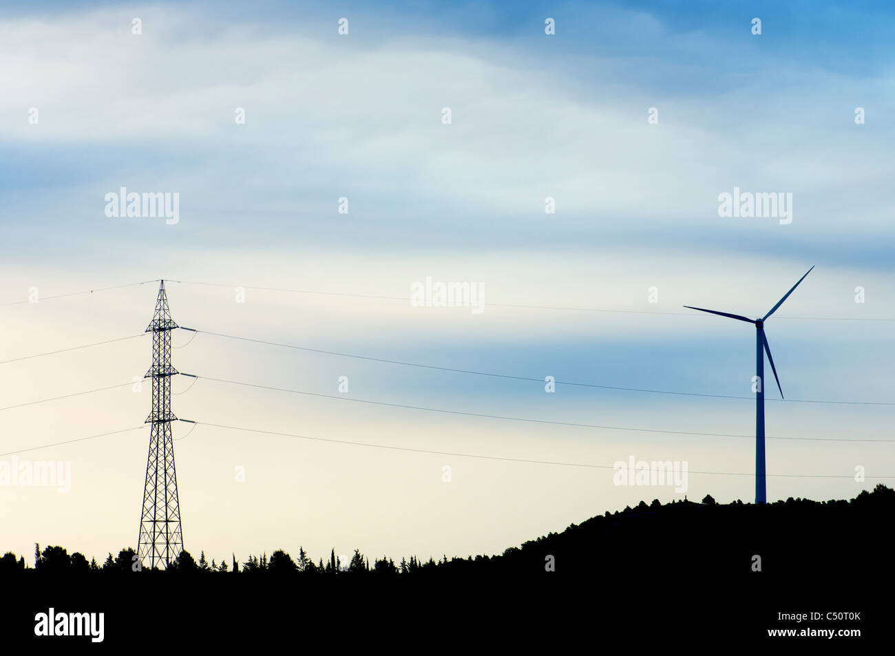 windmill and pylon at sunset cloudy Stock Photo - Alamy