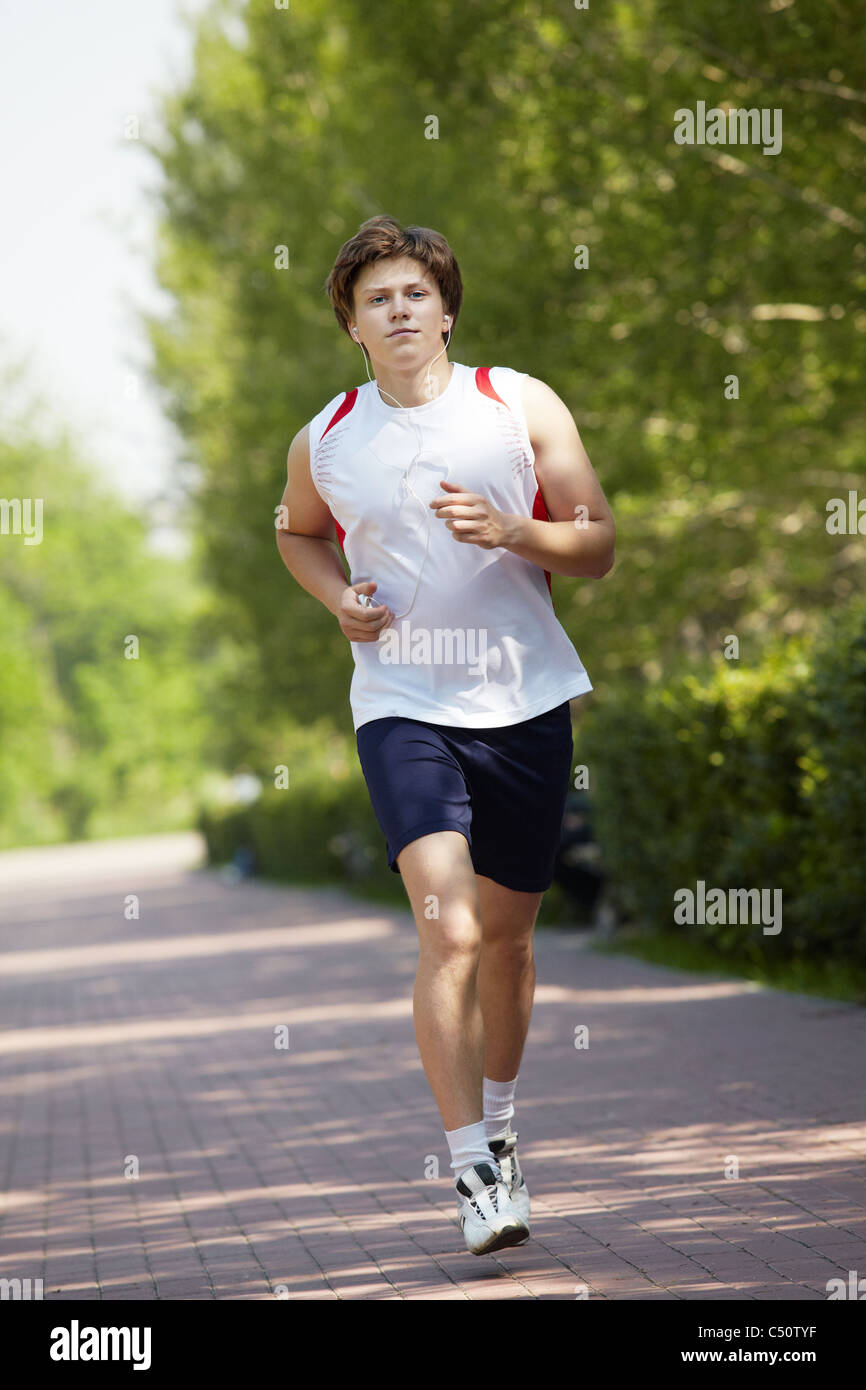 Portrait of a young man jogging with a walkman in park Stock Photo - Alamy