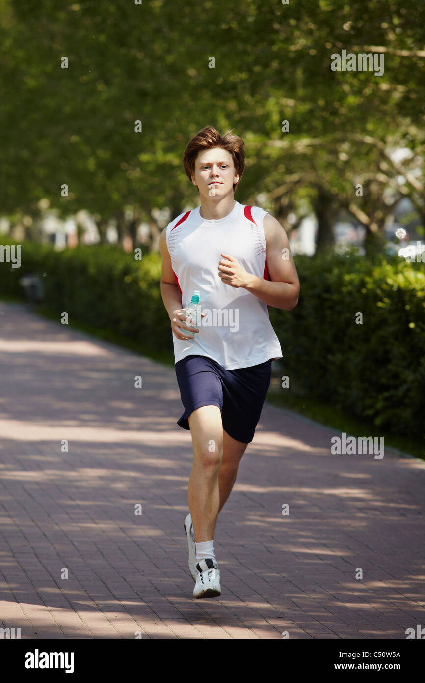 Portrait of active young man jogging in park Stock Photo - Alamy