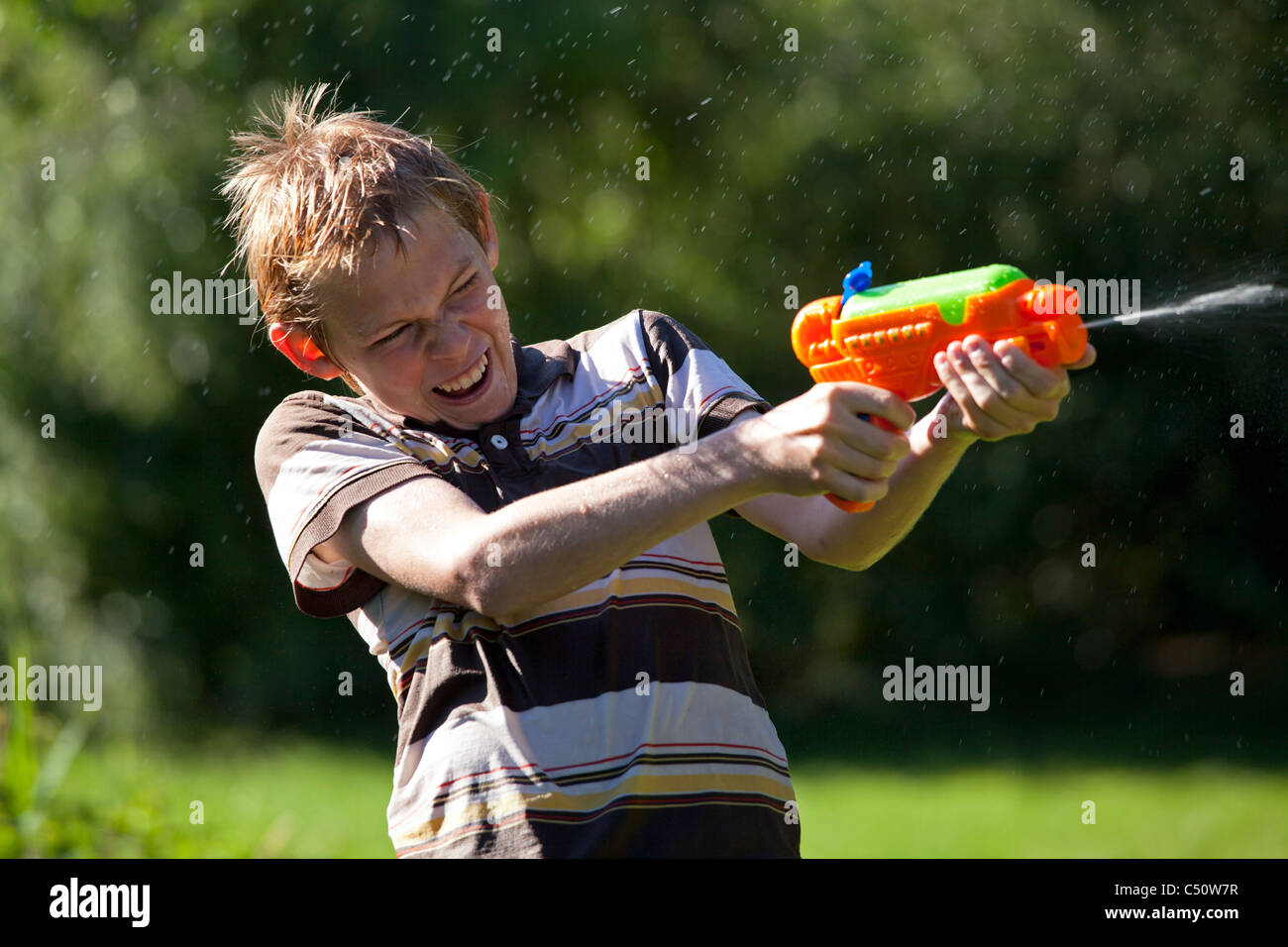 young boy shooting with a water pistol Stock Photo - Alamy